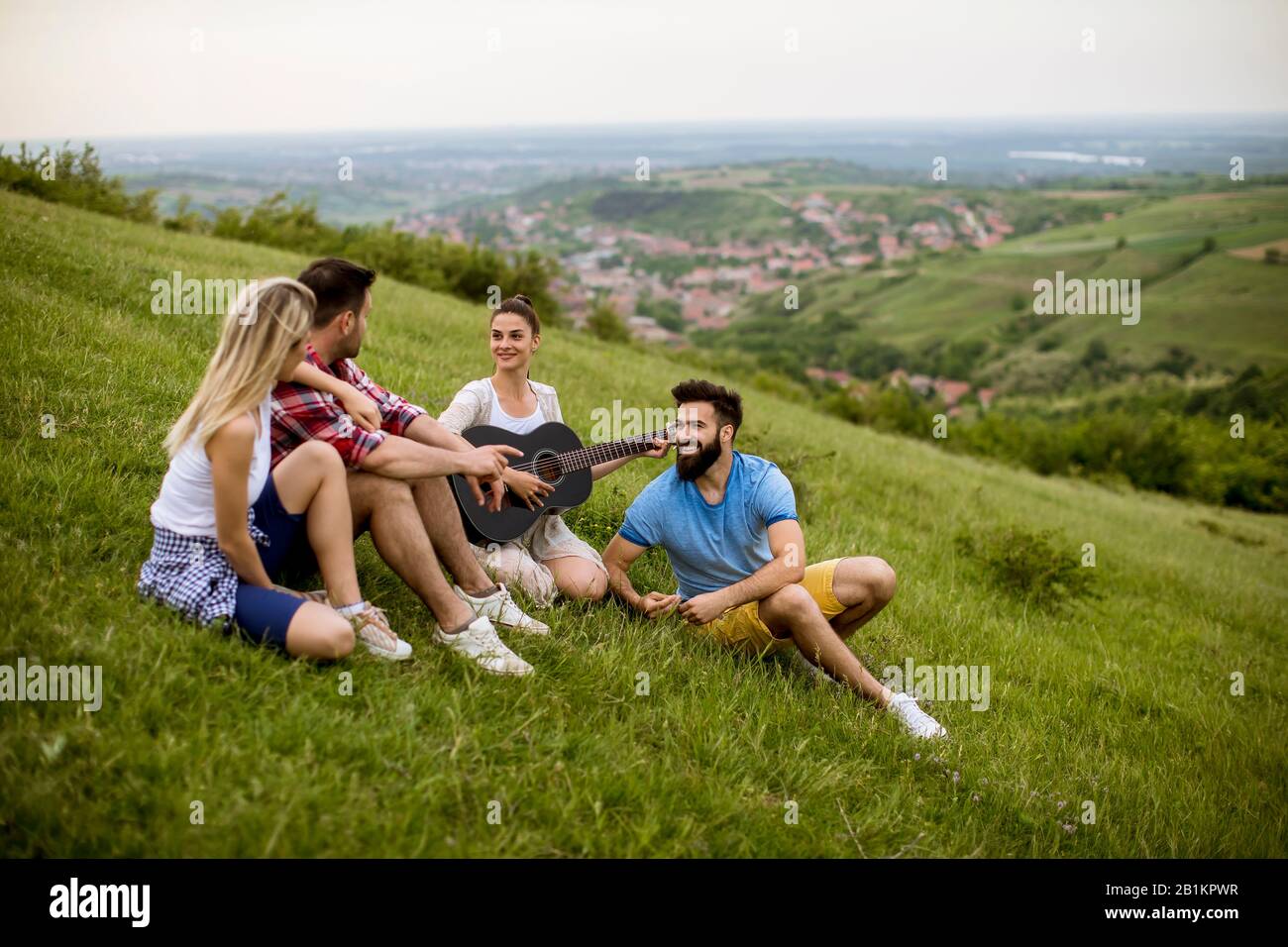 Group od young people sitting on grass and having fun on a field trip ...