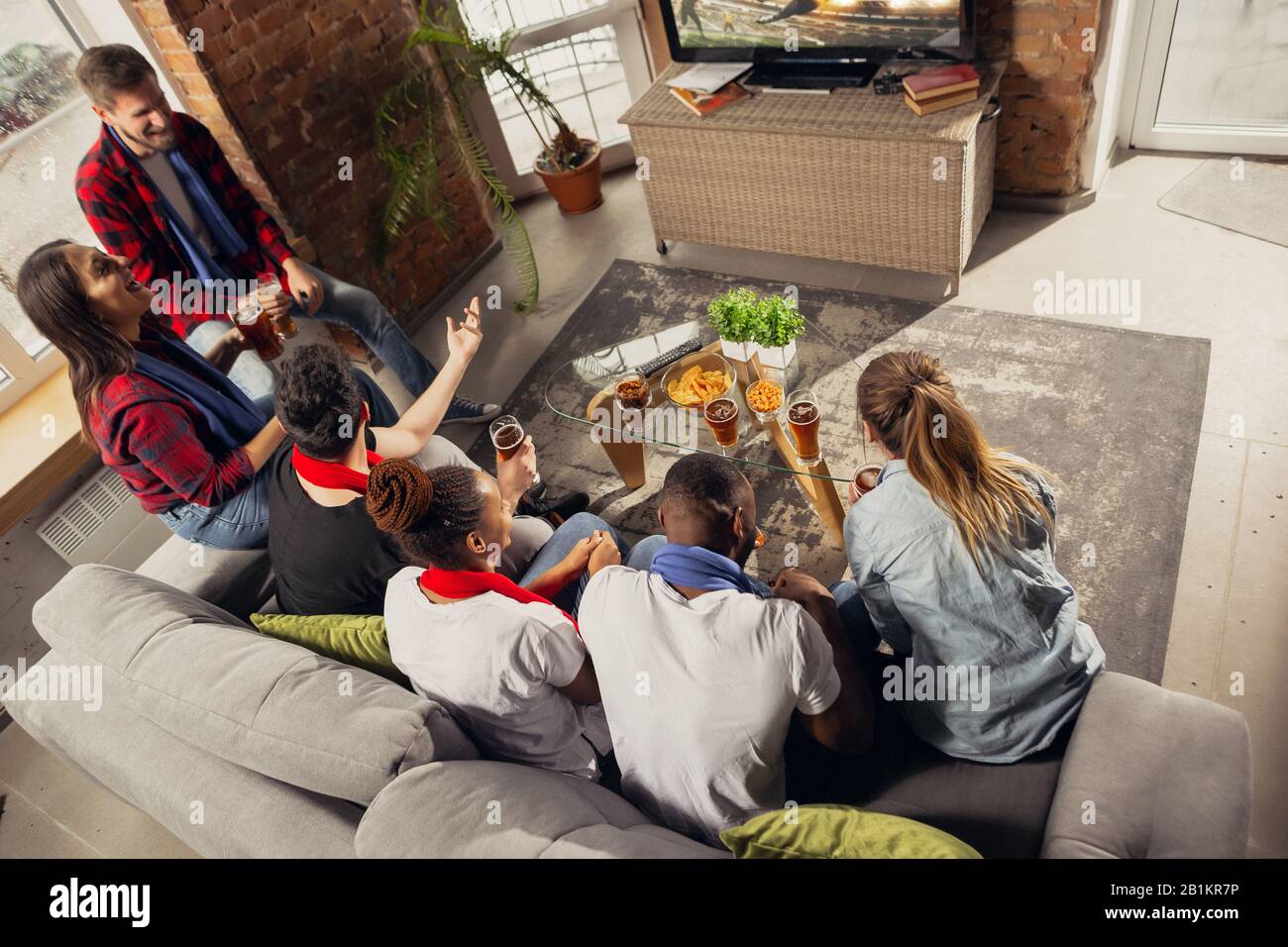 Excited group of people watching rugby, sport match at home ...
