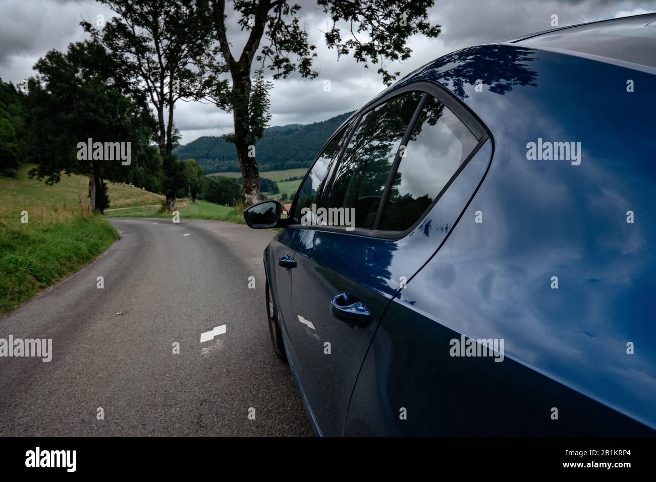 Blue car on beautiful way with the background of the road to forest ...