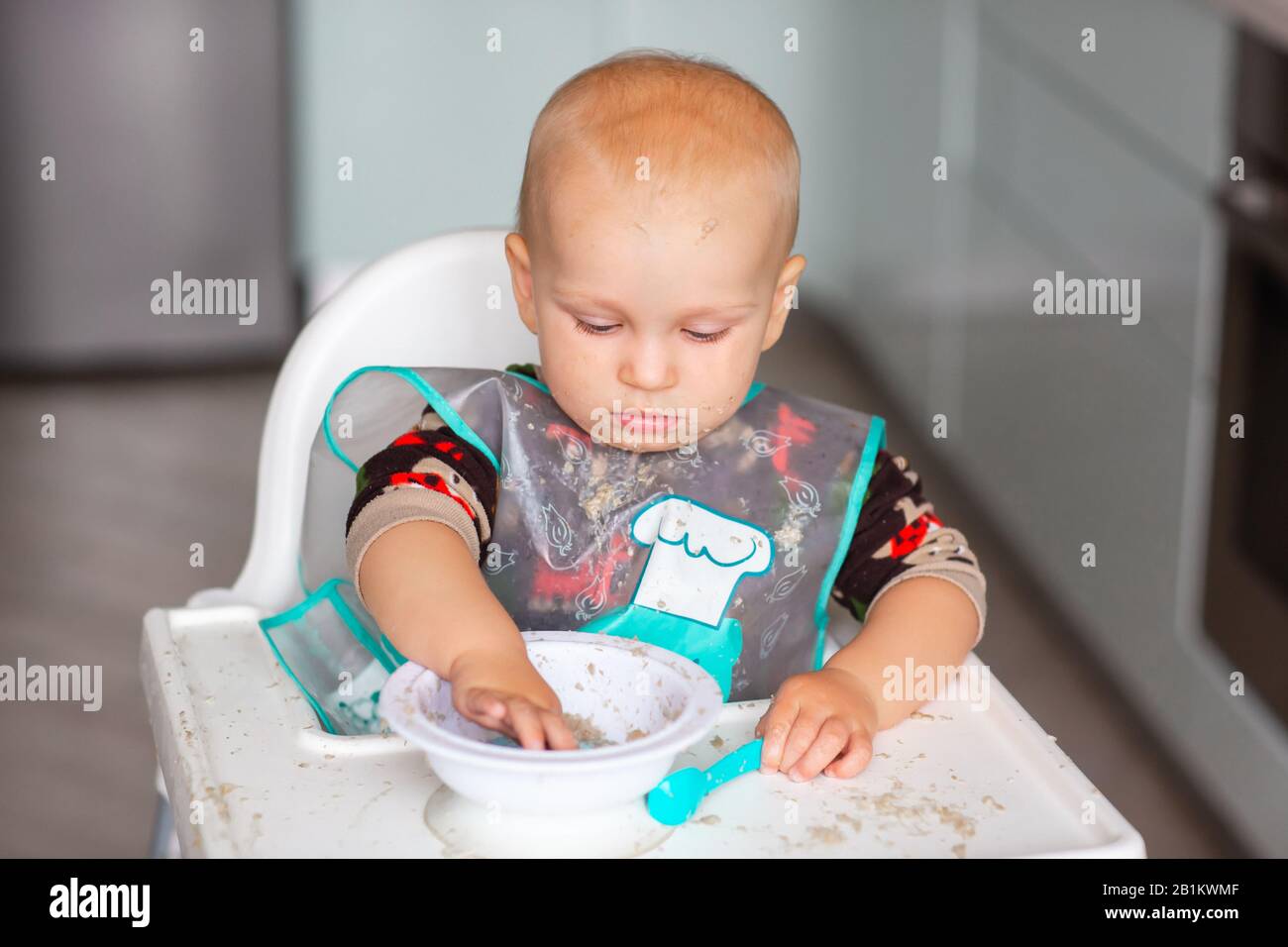 Cute little baby eating his first porridge. Supplementary food for ...