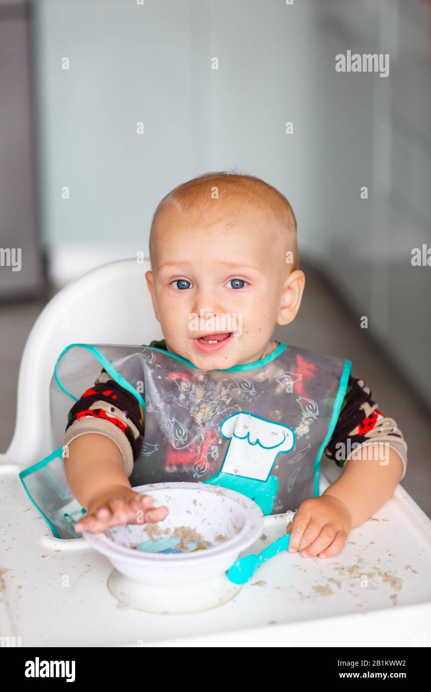Cute little baby eating his first porridge. Supplementary food for ...