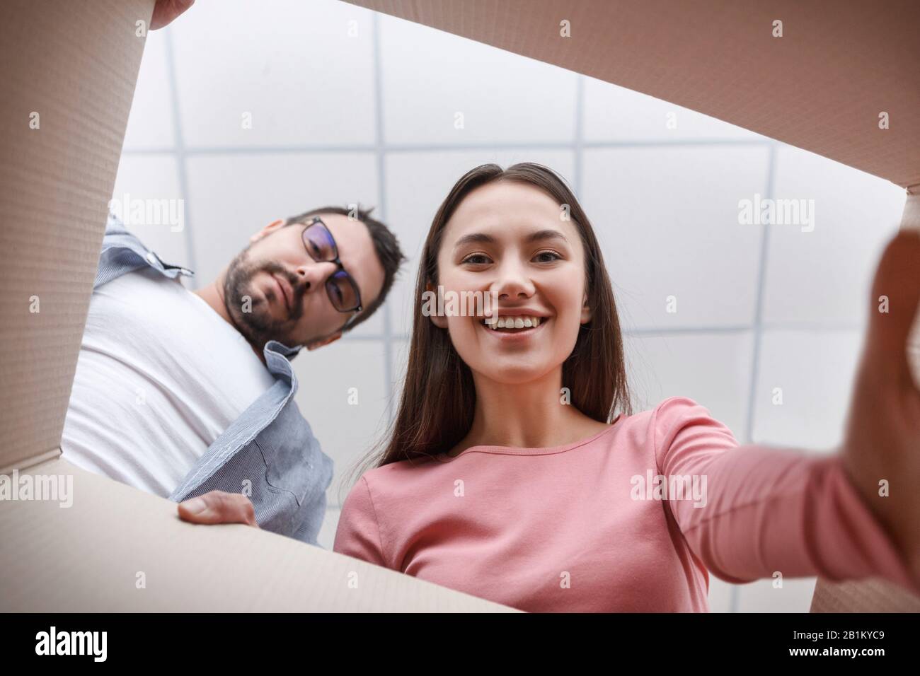 Positive young couple looking into a cardboard box Stock Photo - Alamy