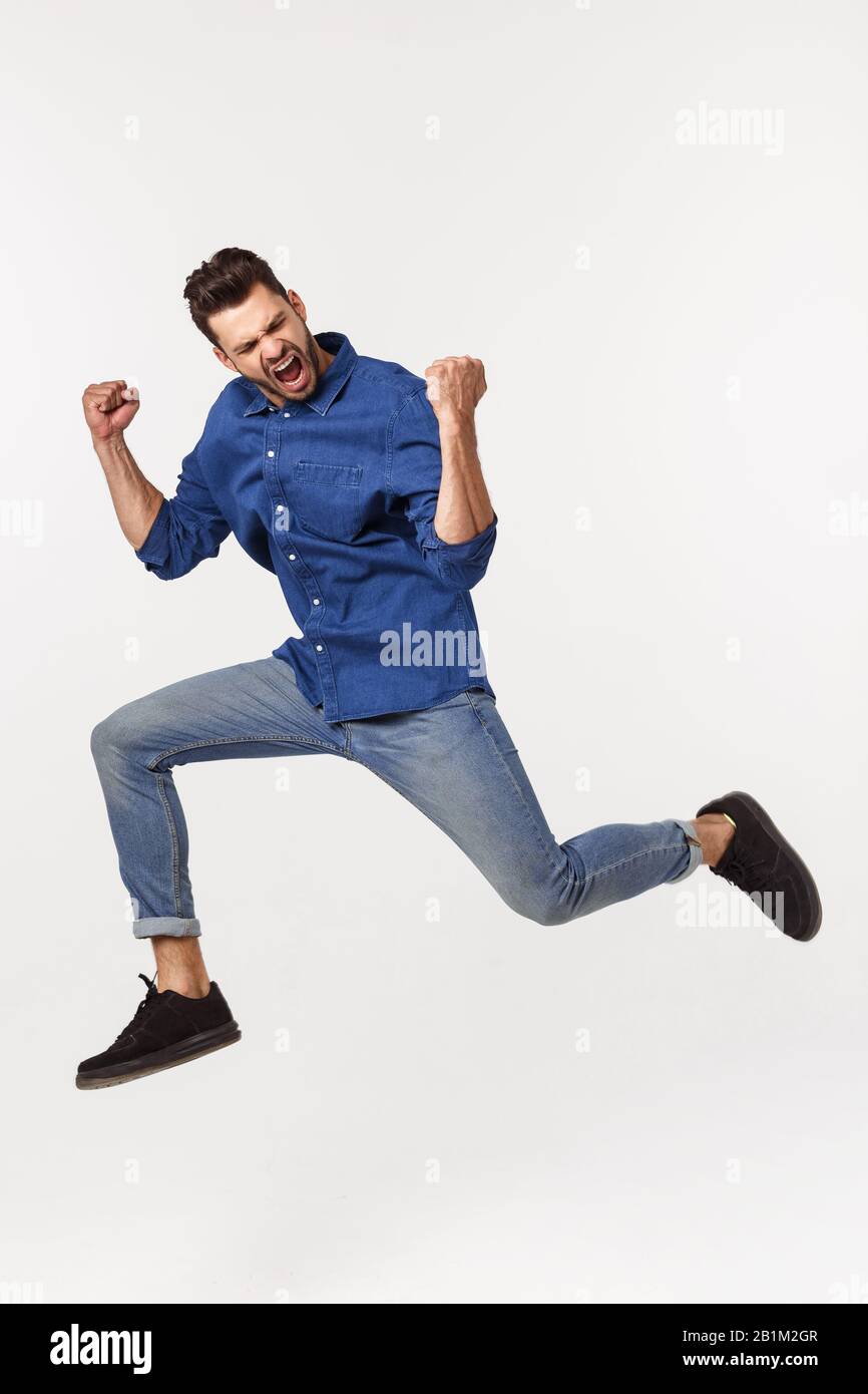 An attractive athletic businessman jumping up against white background ...