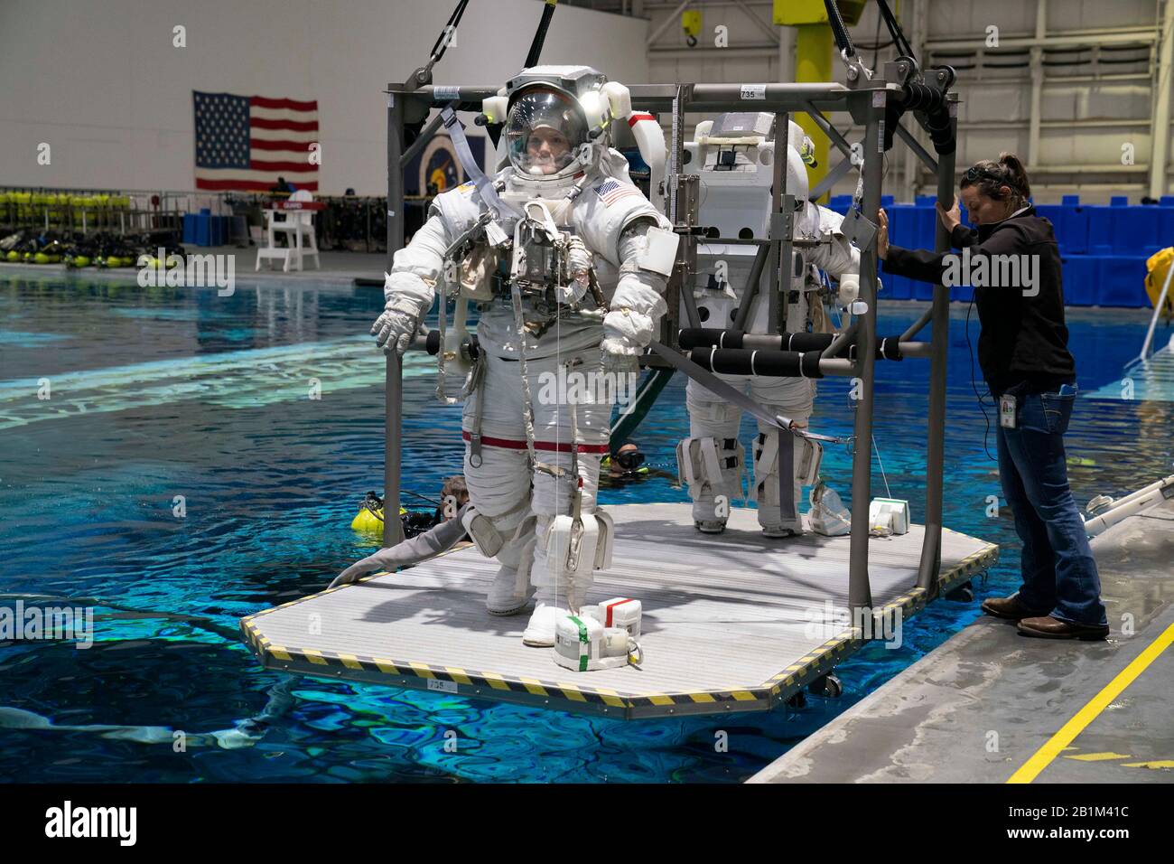 An overhead crane lowers astronauts Anne C. McClain and Zena Cardman ...