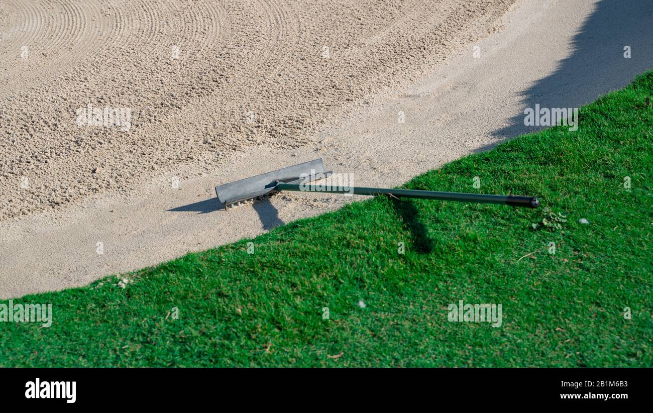 Rake in the sand trap on a golf course course Stock Photo - Alamy