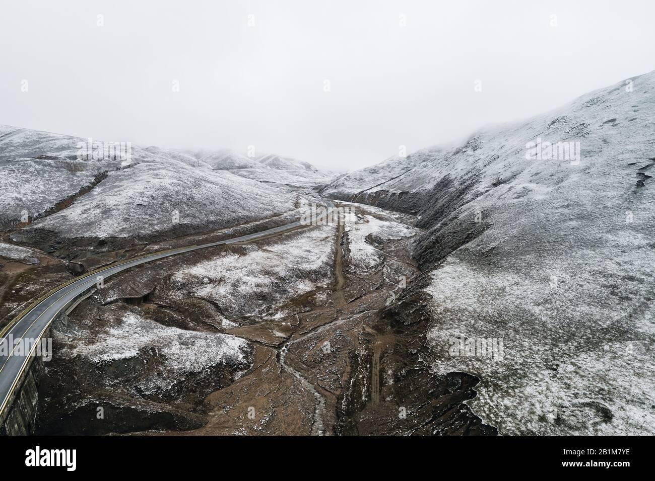 Country road winding through a valley surrounded by snowy mountains ...