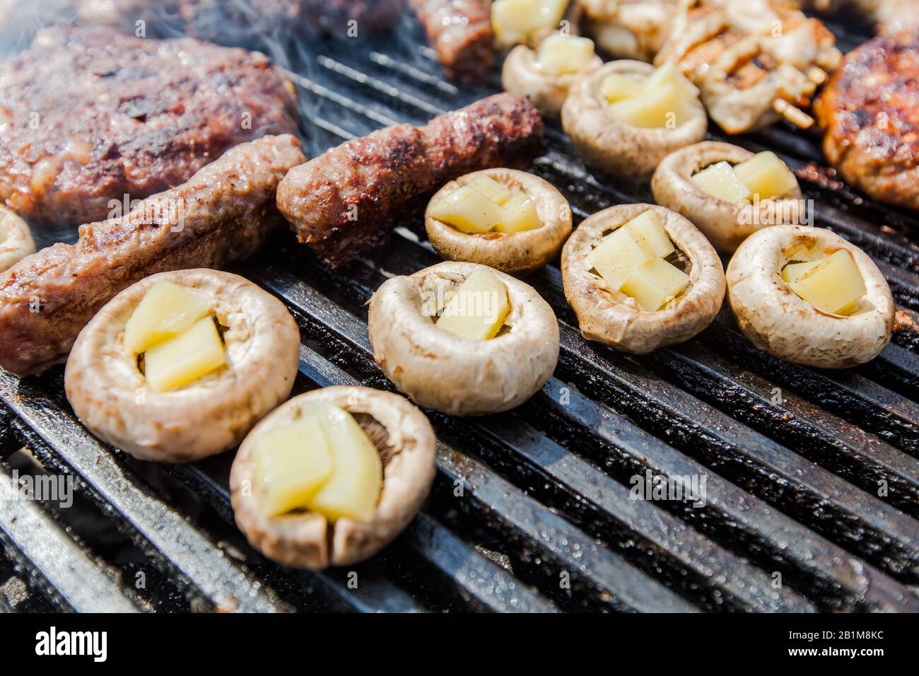 Assortment of grilled meat and filled white champignon on barbecue. BBQ ...