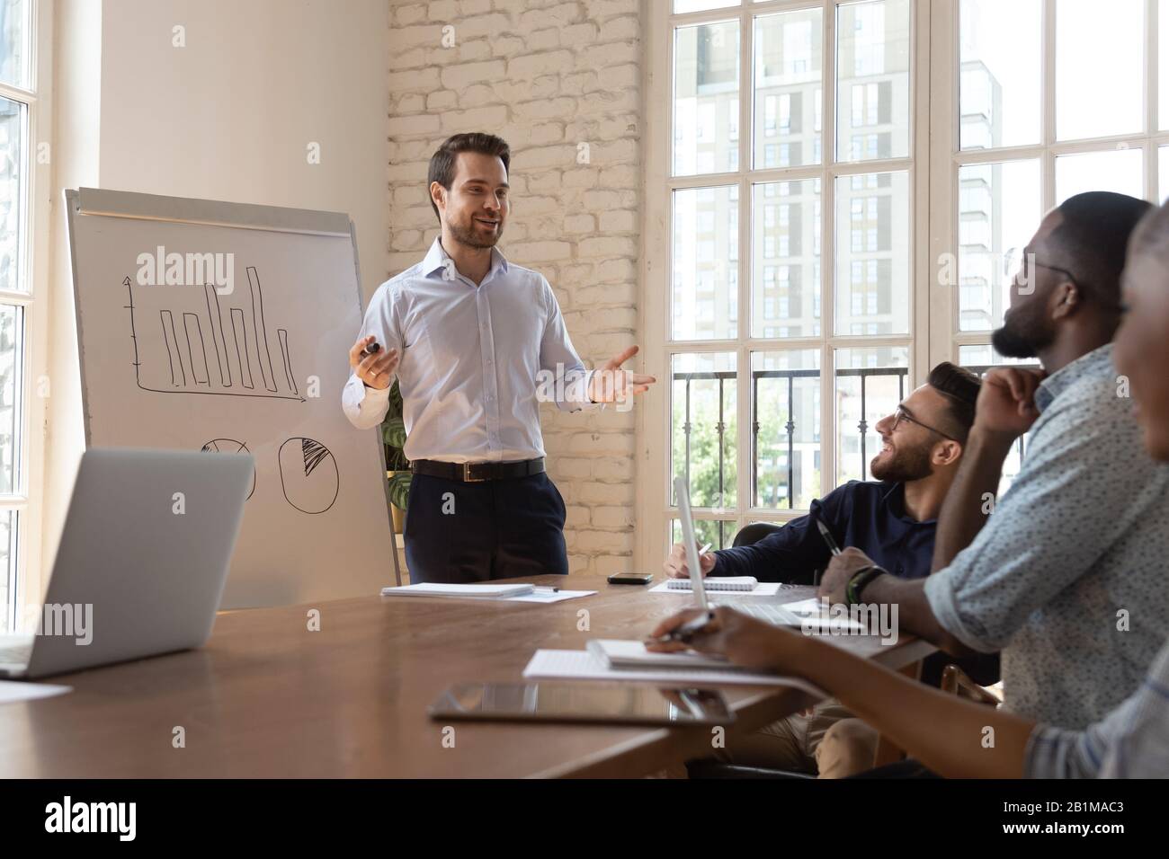 Business trainer stands in front of diverse team makes presentation ...