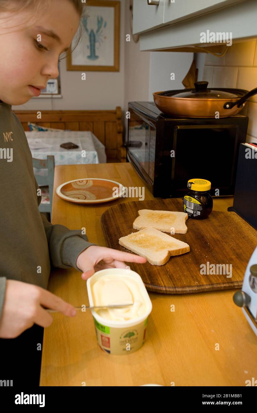 young girl preparing her butter and marmite on toast Stock Photo - Alamy