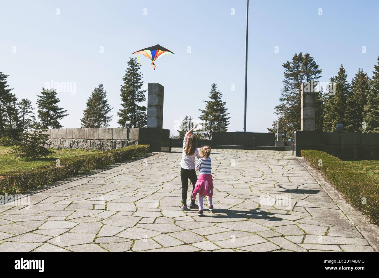 Two little girls fun with colorful flying kite in the park at spring ...