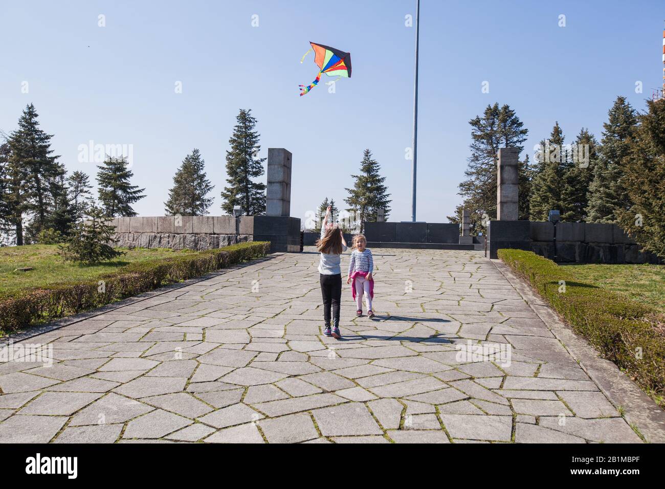 Two little girls fun with colorful flying kite in the park at spring ...
