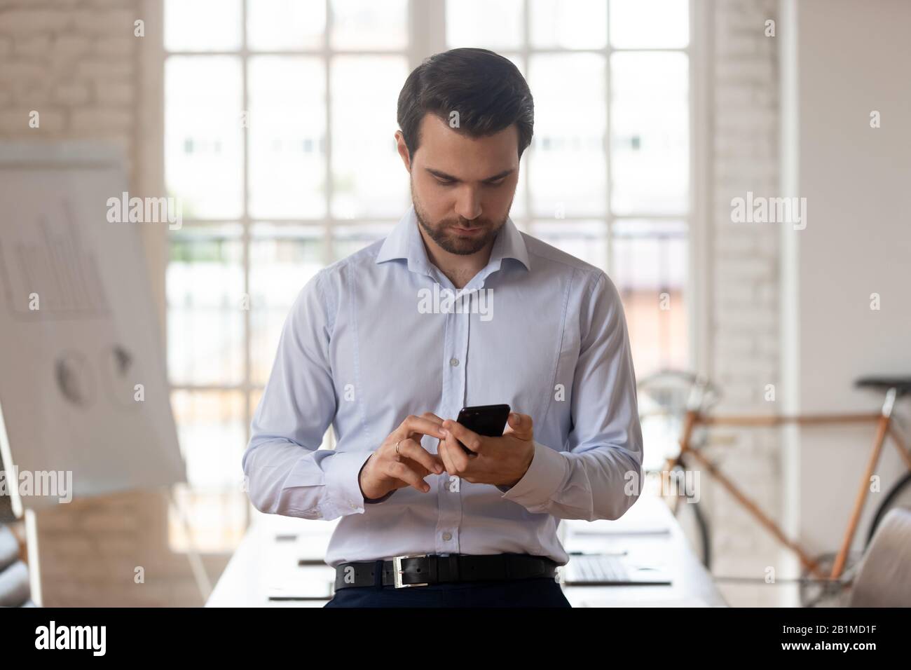 Focused on chat businessman standing inside of modern light boardroom ...