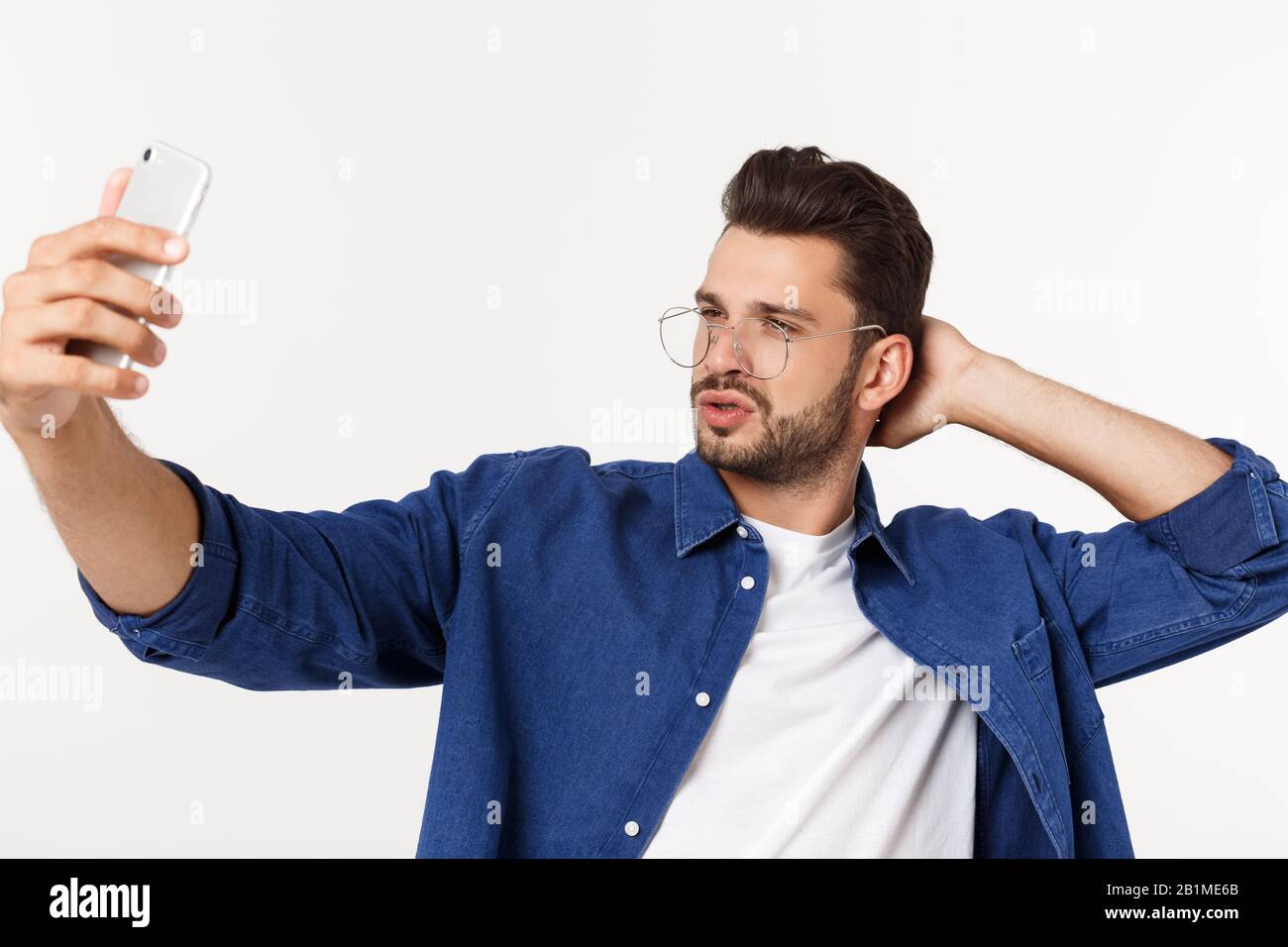 Portrait of an attractive young man taking a selfie while standing and ...