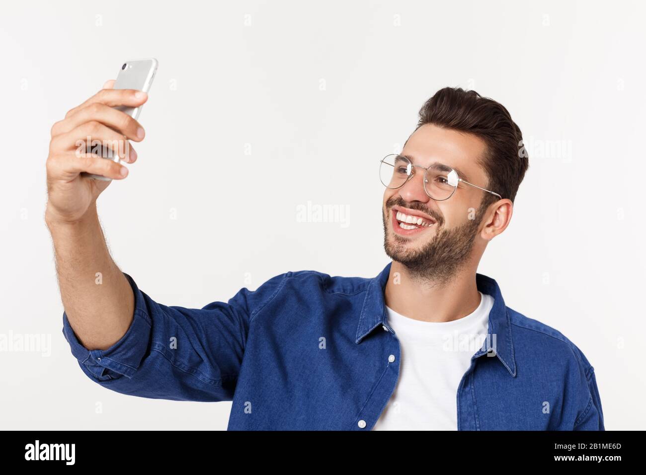 Portrait of an attractive young man taking a selfie while standing and ...