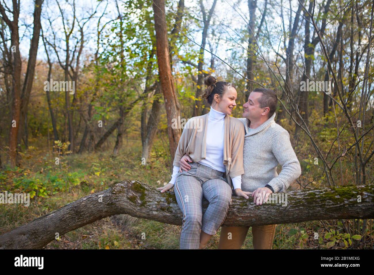 Beautiful couple sitting together on the tree in park hugging Stock ...