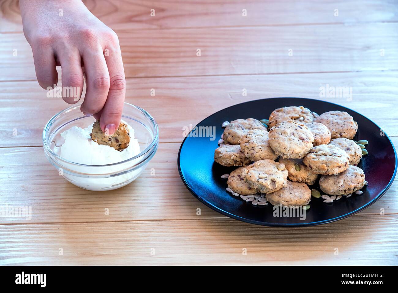 Female Hand dipping Salted crispy integral cracker with sunflower and ...
