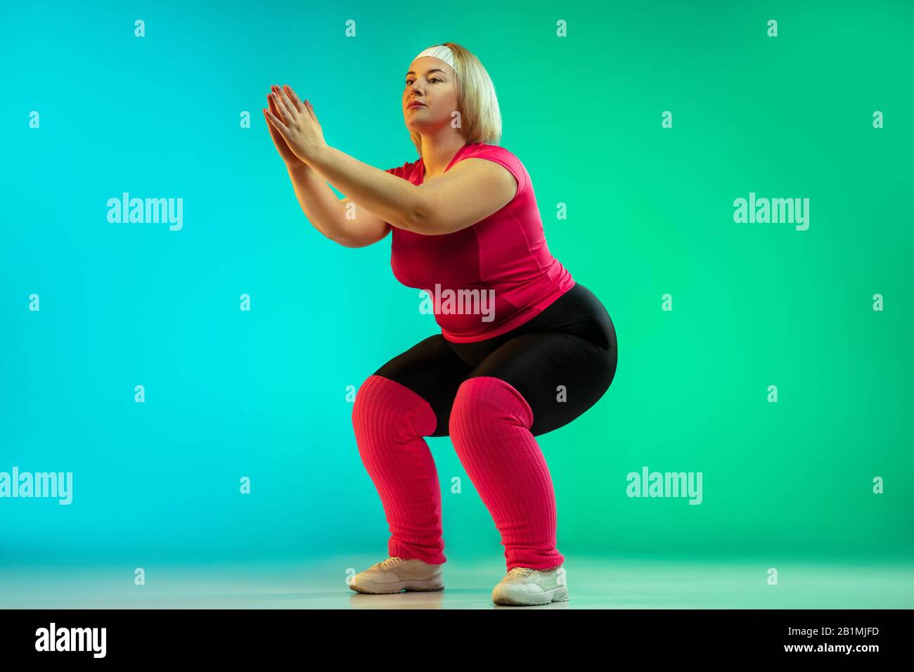 Young caucasian plus size female model's training on gradient green ...