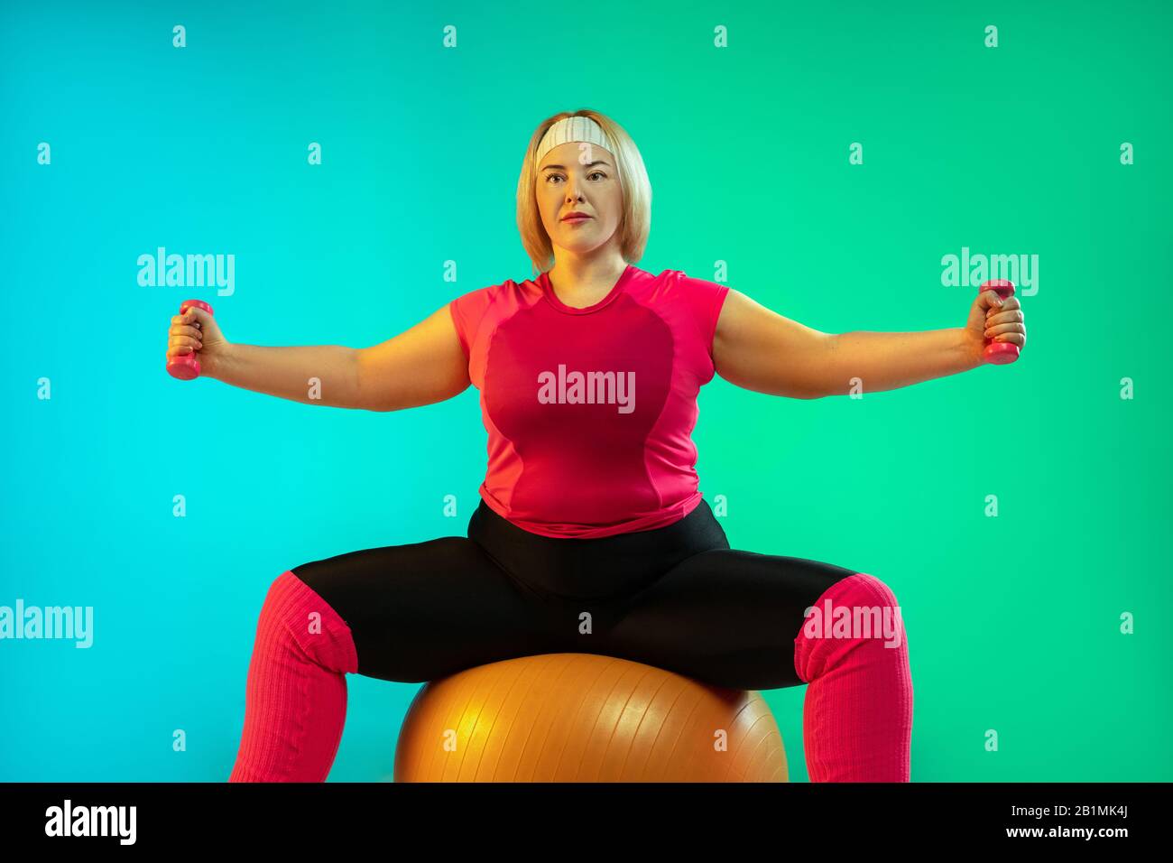 Young caucasian plus size female model's training on gradient green ...