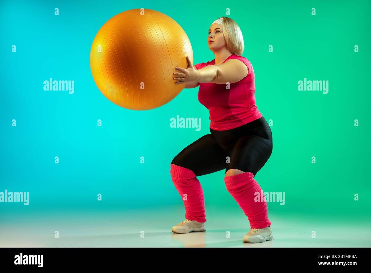 Young caucasian plus size female model's training on gradient green ...