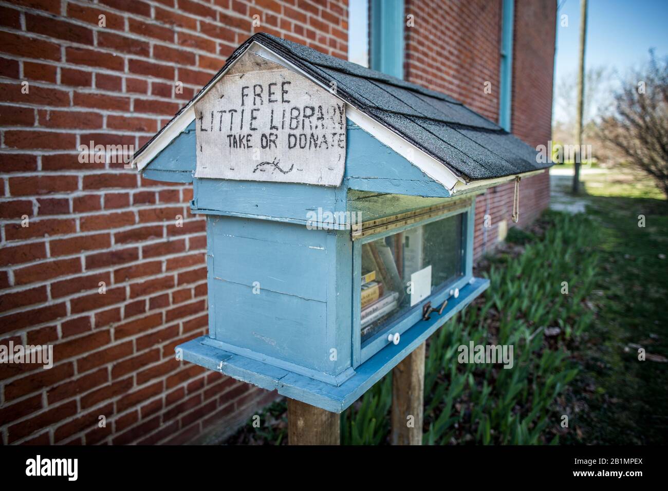 A shot of a free little library sitting along a sidewalk in a small ...