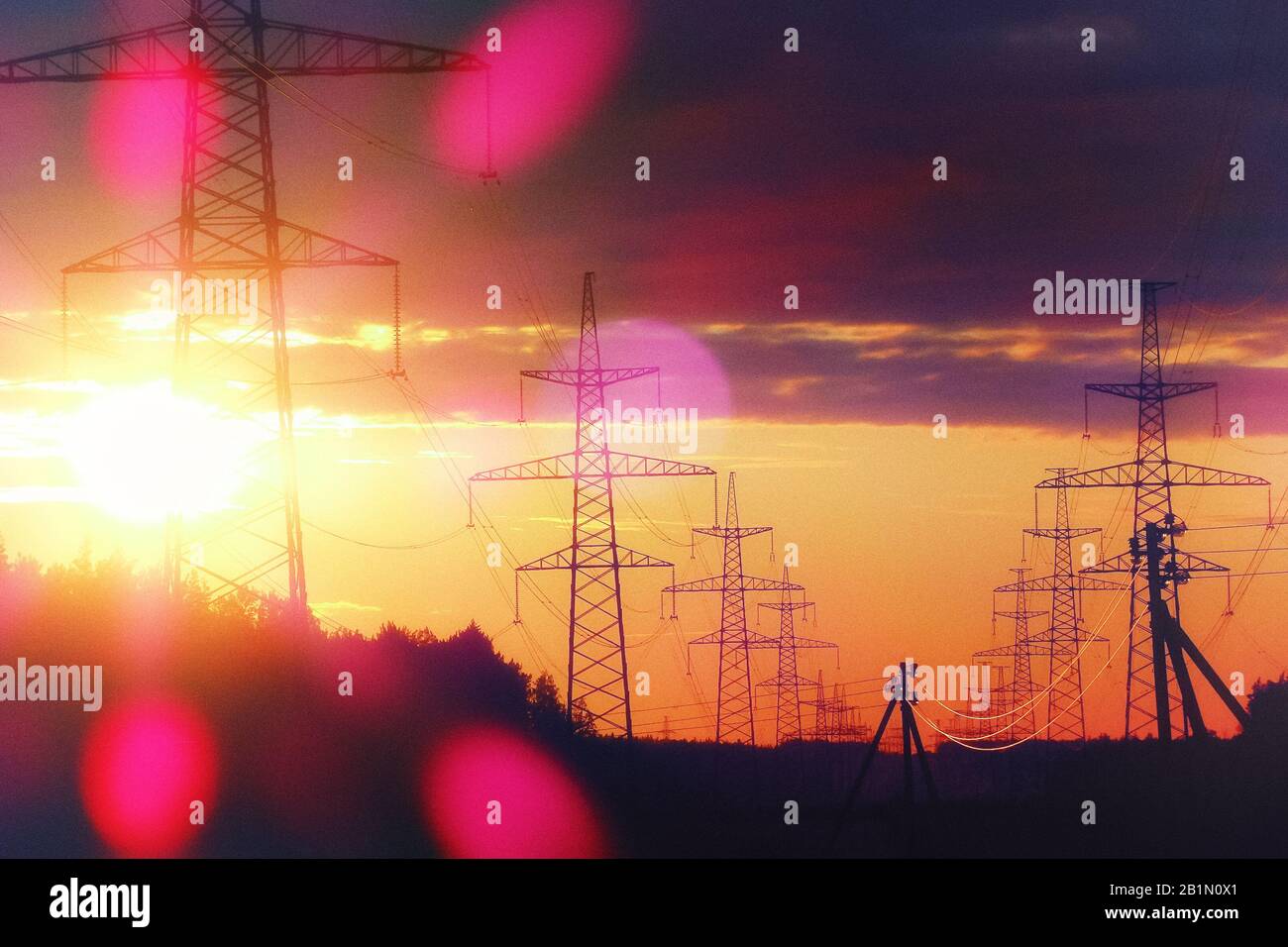 Far-reaching power lines against the backdrop of a bright setting sun ...
