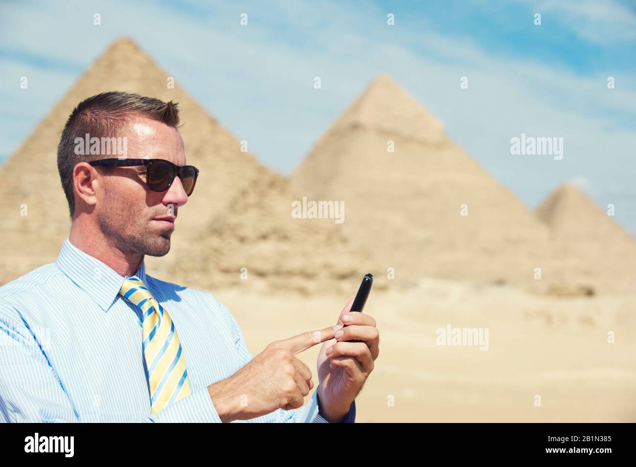 Businessman using his smartphone in desert sun against background of ...