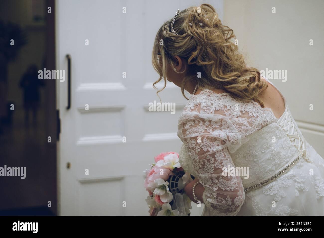 A nervous bride before her wedding peeking through the church door ...
