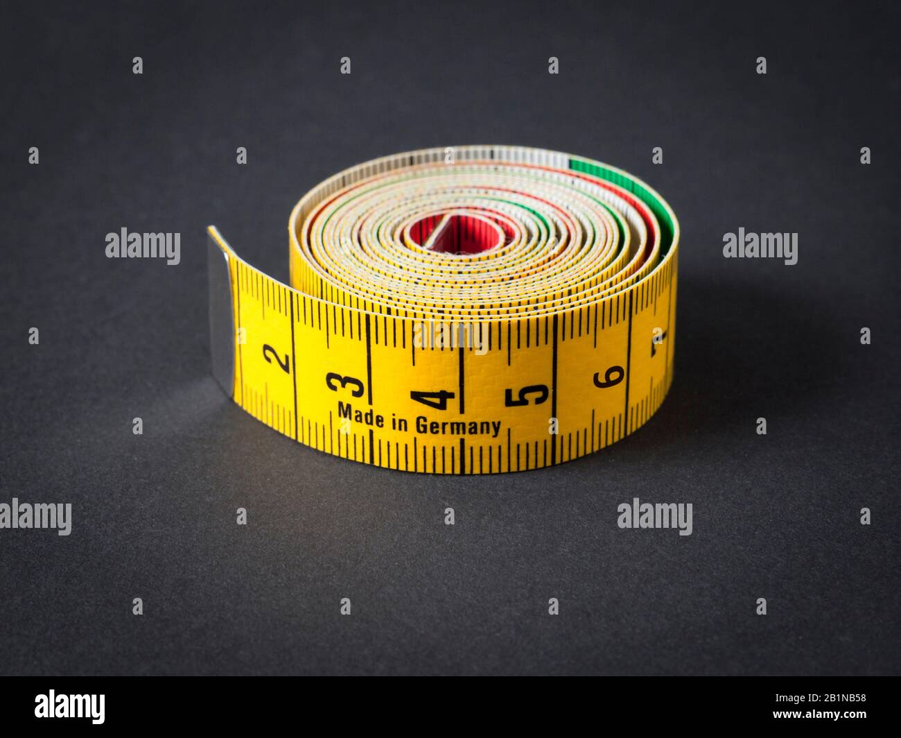 3D computer graphic, furled yellow measuring tape against grey ...