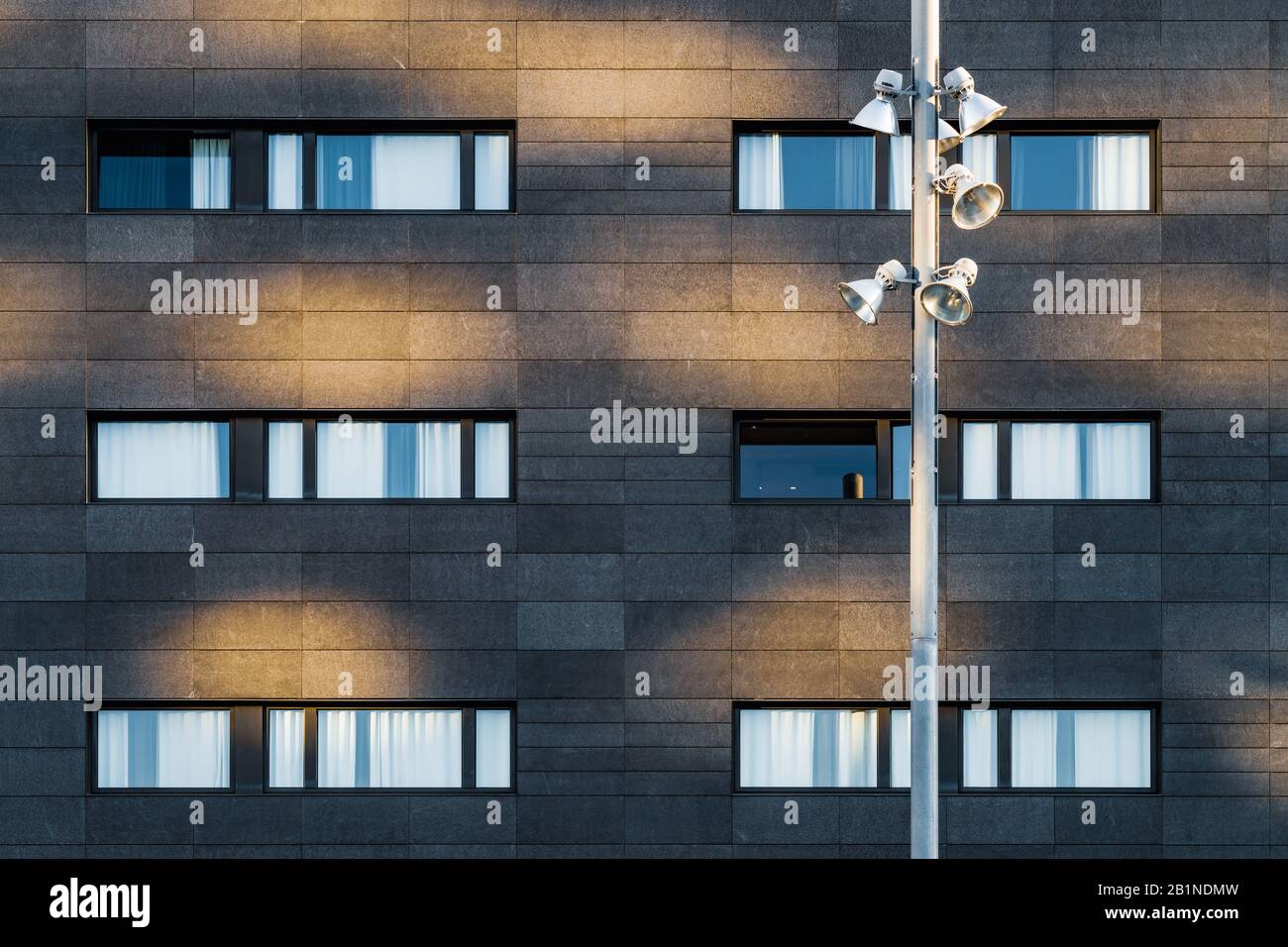 Streetlight and black facade of an urban building with long horizontal ...