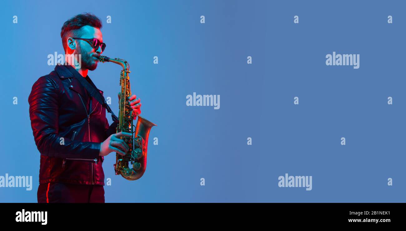 Young caucasian jazz musician playing the saxophone on gradient blue ...