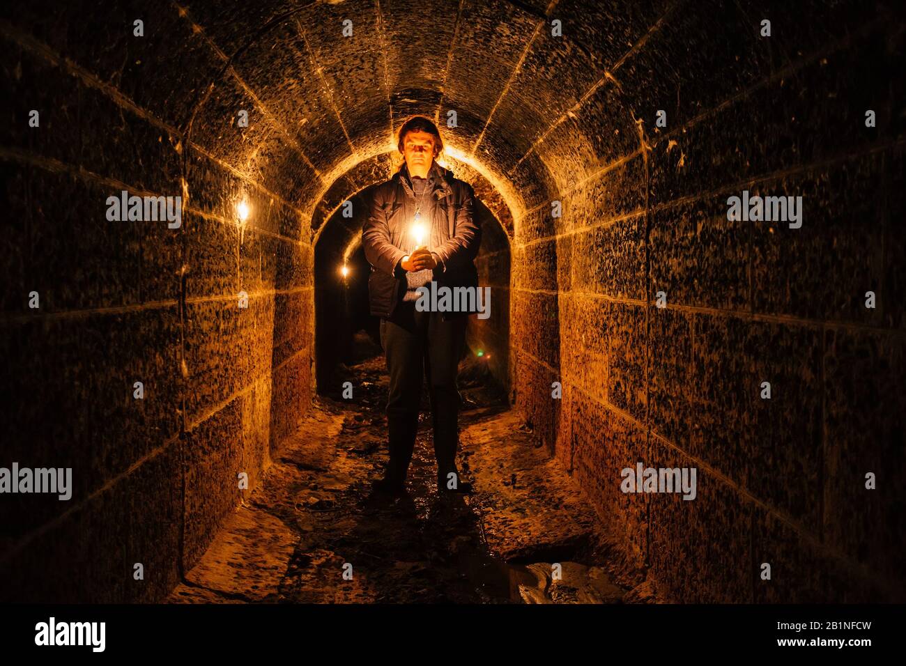 Urban explorer with candle in old vaulted underground tunnel Stock ...