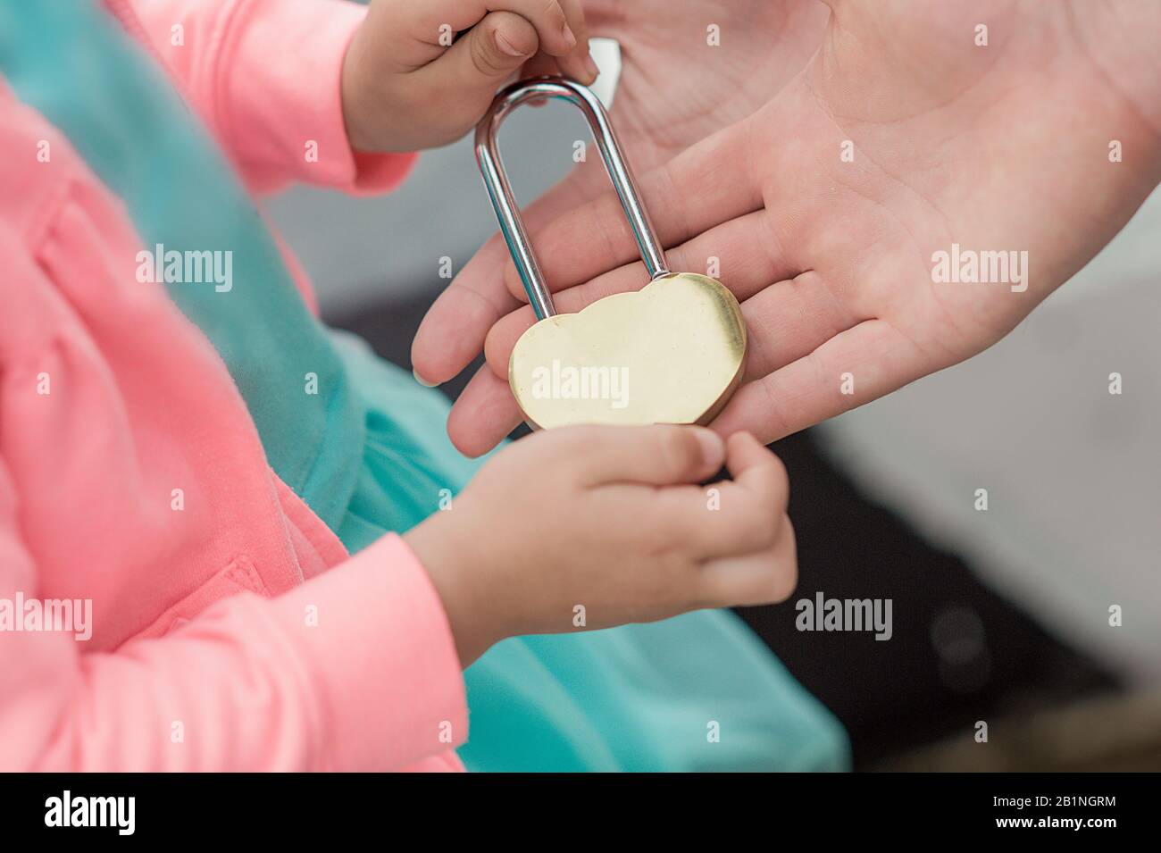 unusual metal gold closed lock in hands, a little girl passes the lock ...