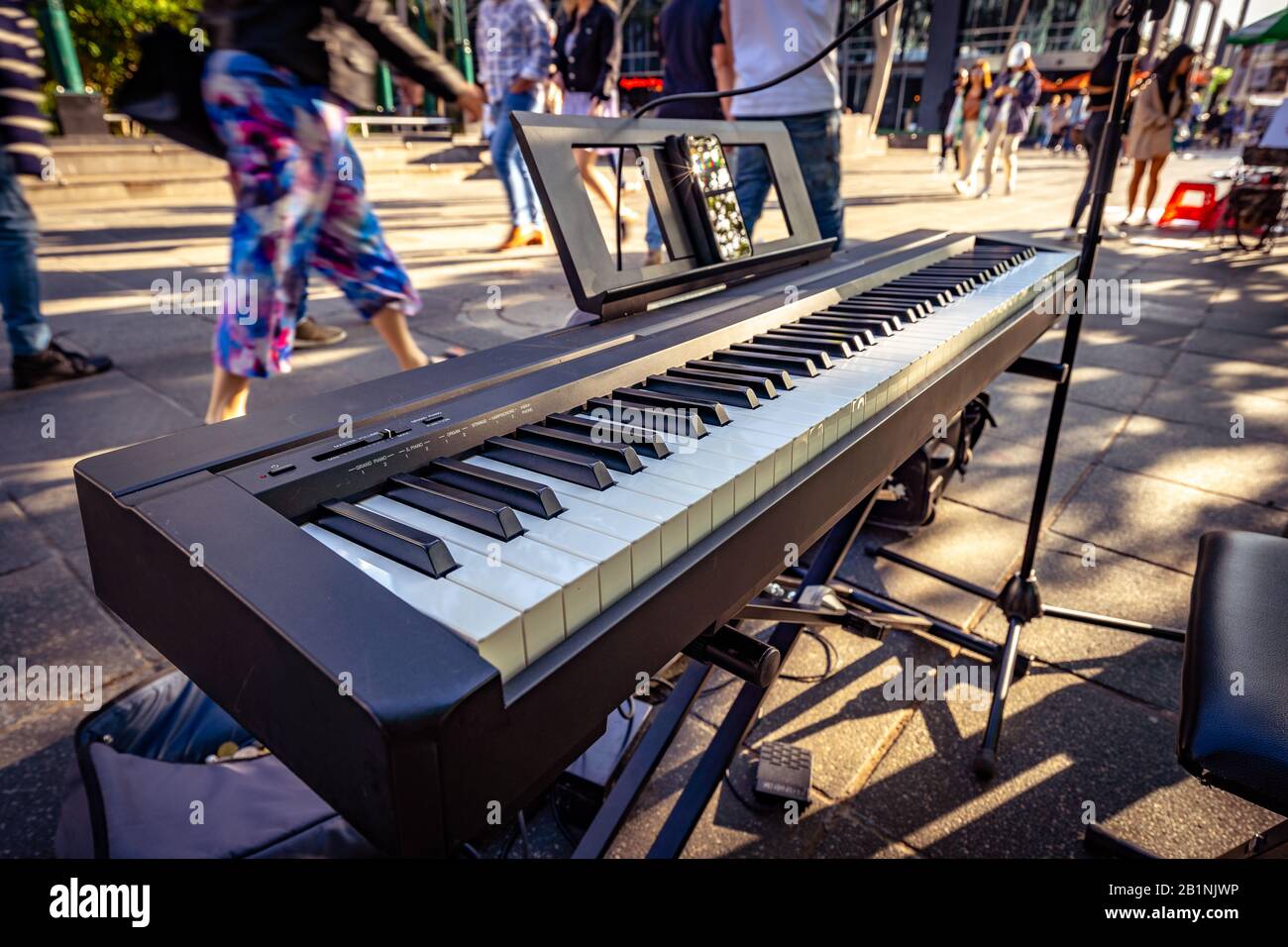Busker's synthesizer keyboard closeup with people walking by Stock ...