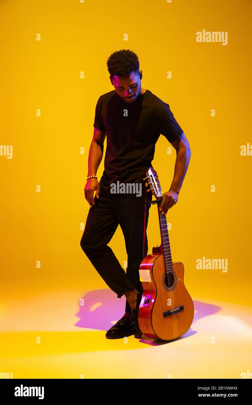 Young and joyful african-american musician playing guitar and singing ...