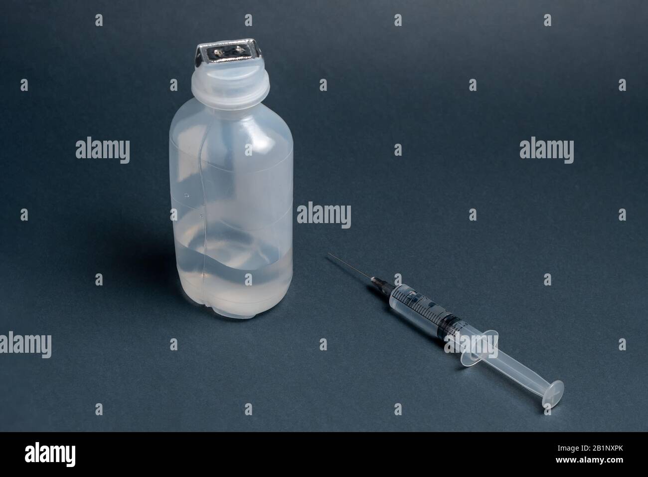 Syringe for injection and medicine in a transparent container on a gray ...