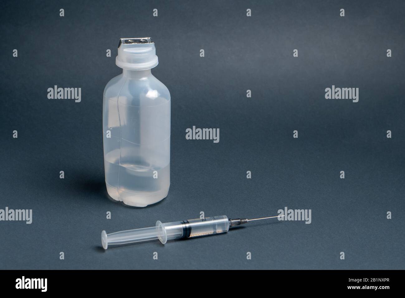 Syringe for injection and medicine in a transparent container on a gray ...