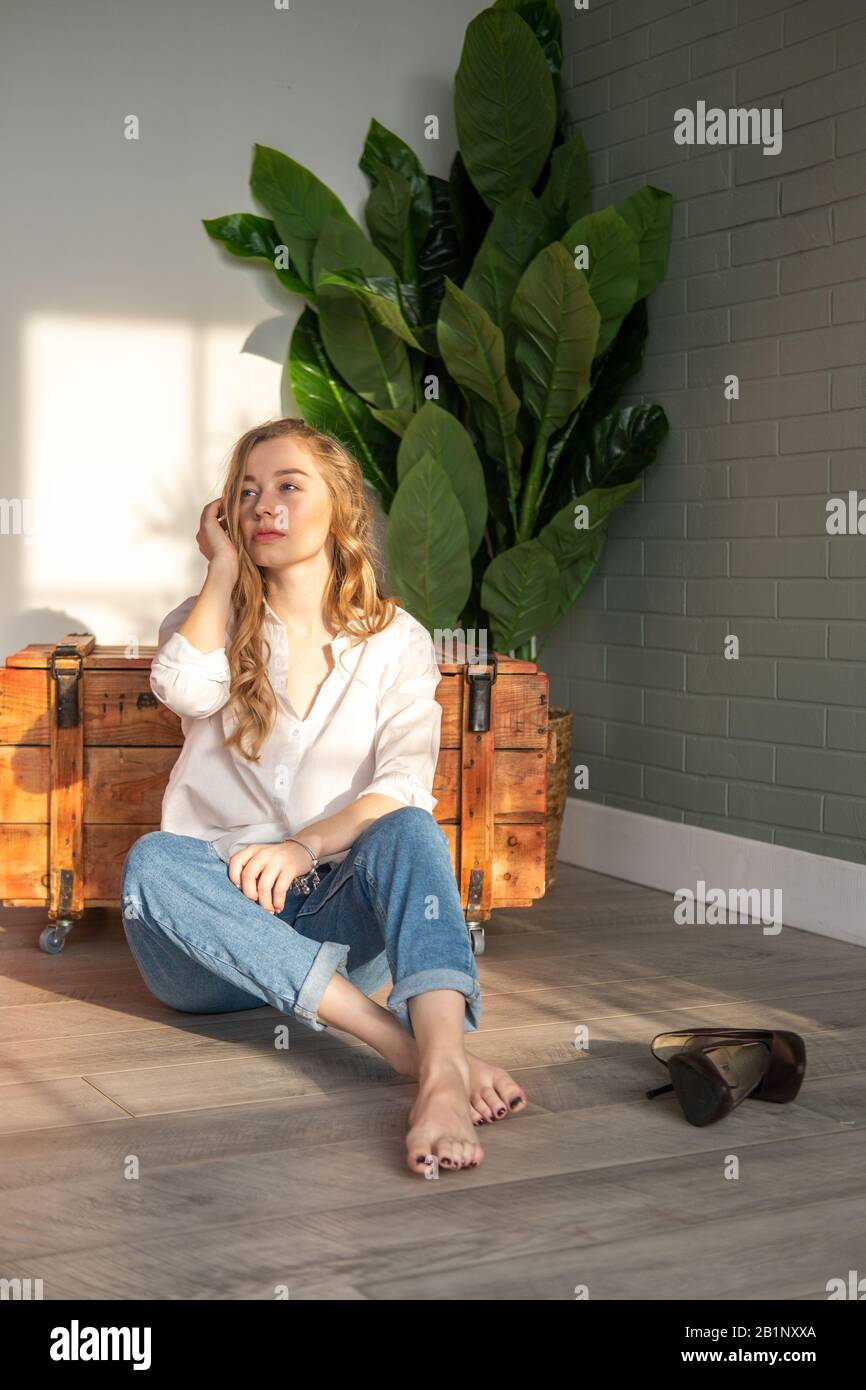Young beautiful woman sitting on the floor with bare feet next to ...