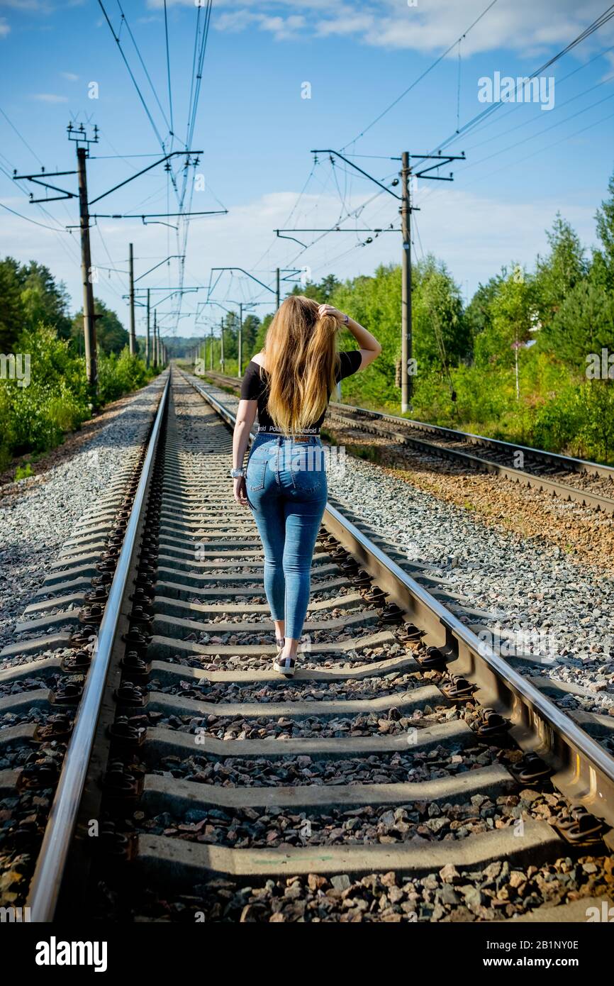 back of the girl walking along the railroad to the destination The girl ...
