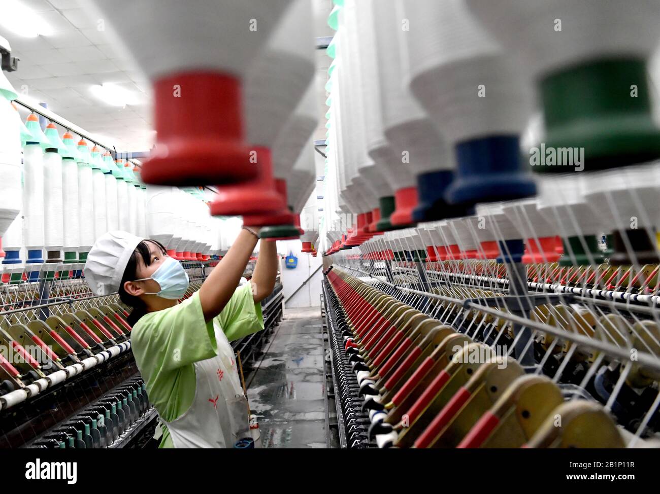A female Chinese worker monitors production of yarn at a textile ...
