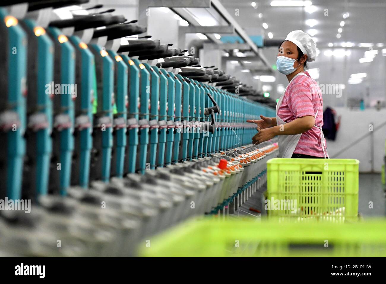 A female Chinese worker monitors production of yarn at a textile ...