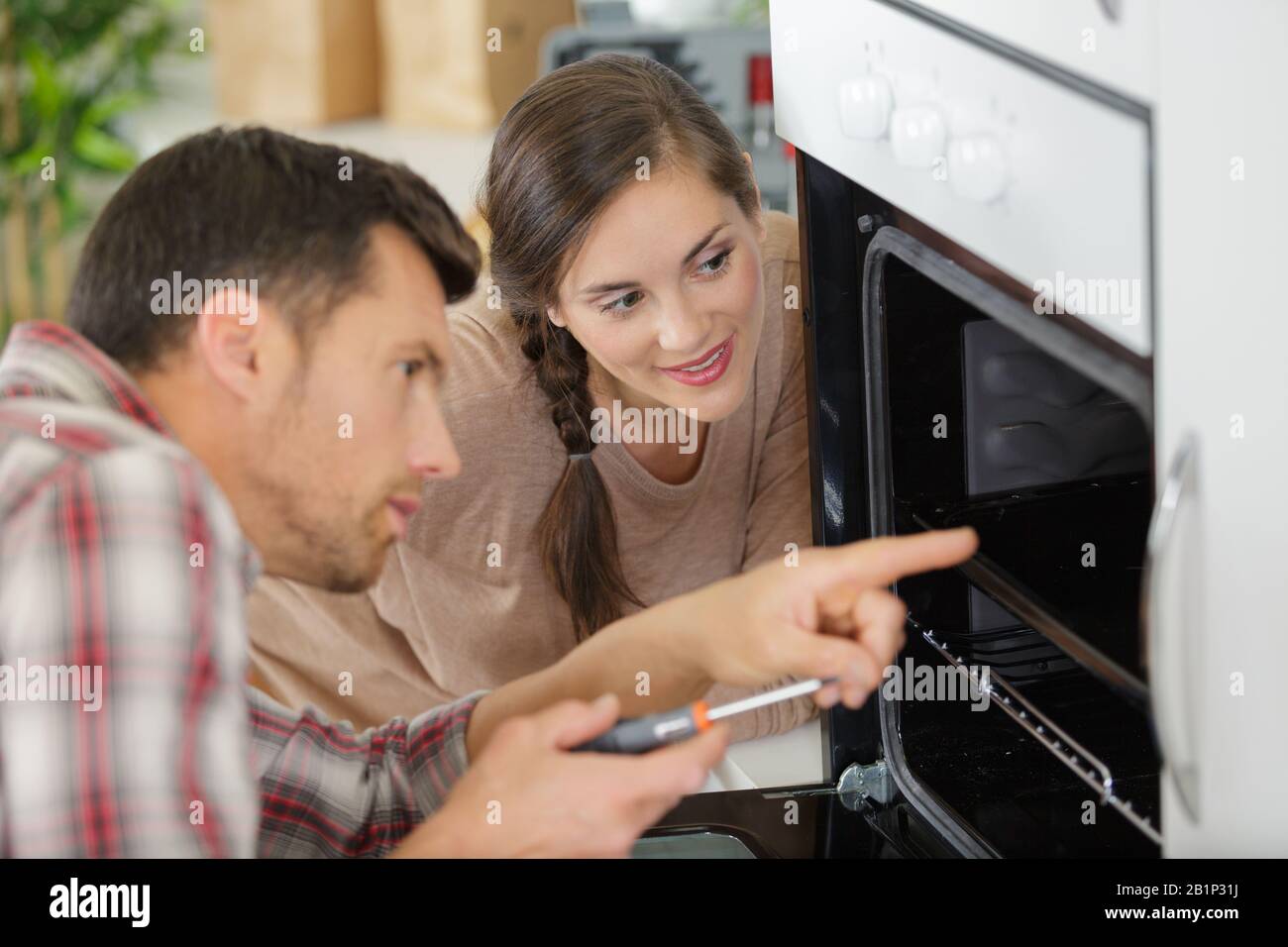 female customer checking oven with worker Stock Photo - Alamy