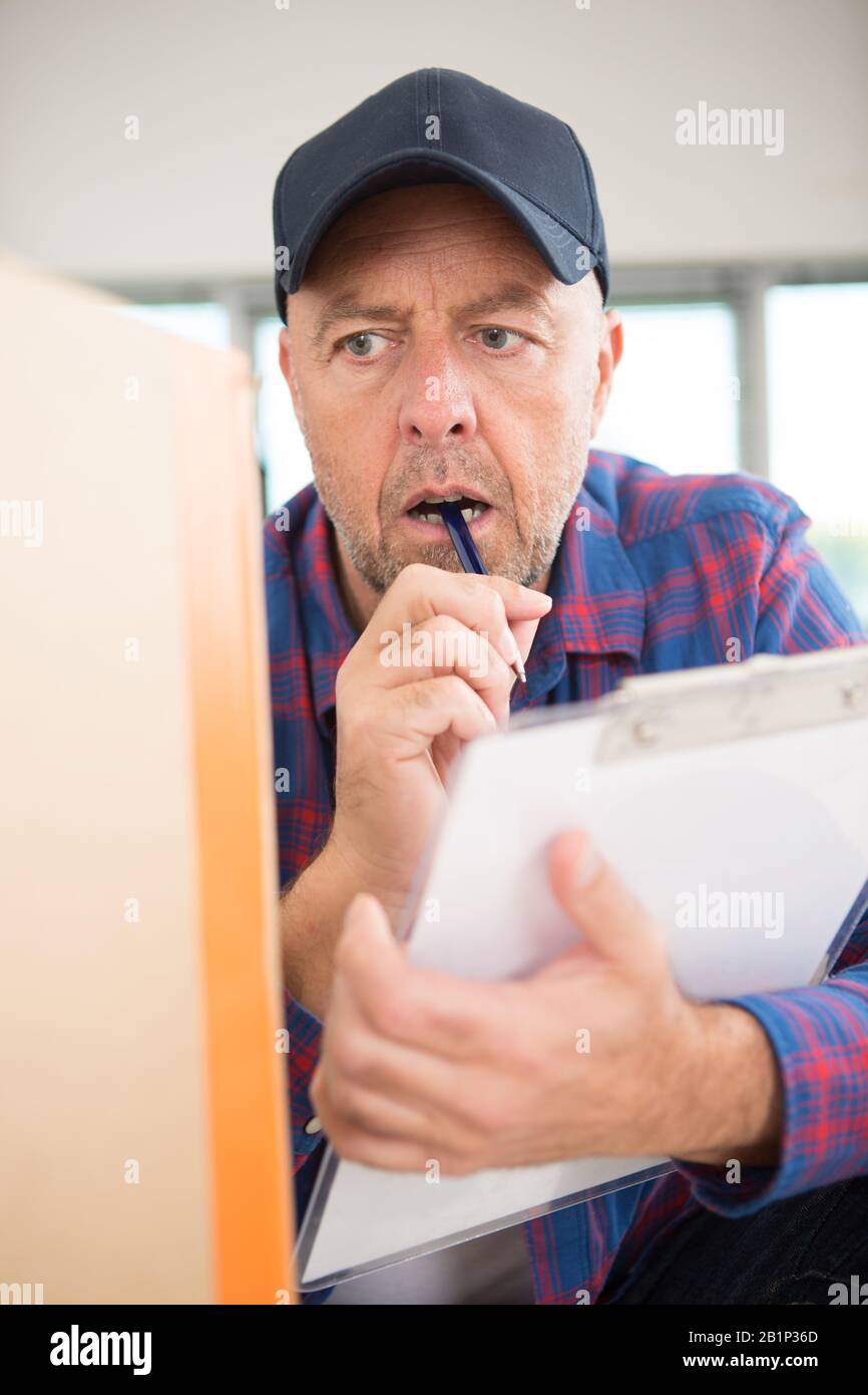 delivery man in uniform checking box Stock Photo - Alamy
