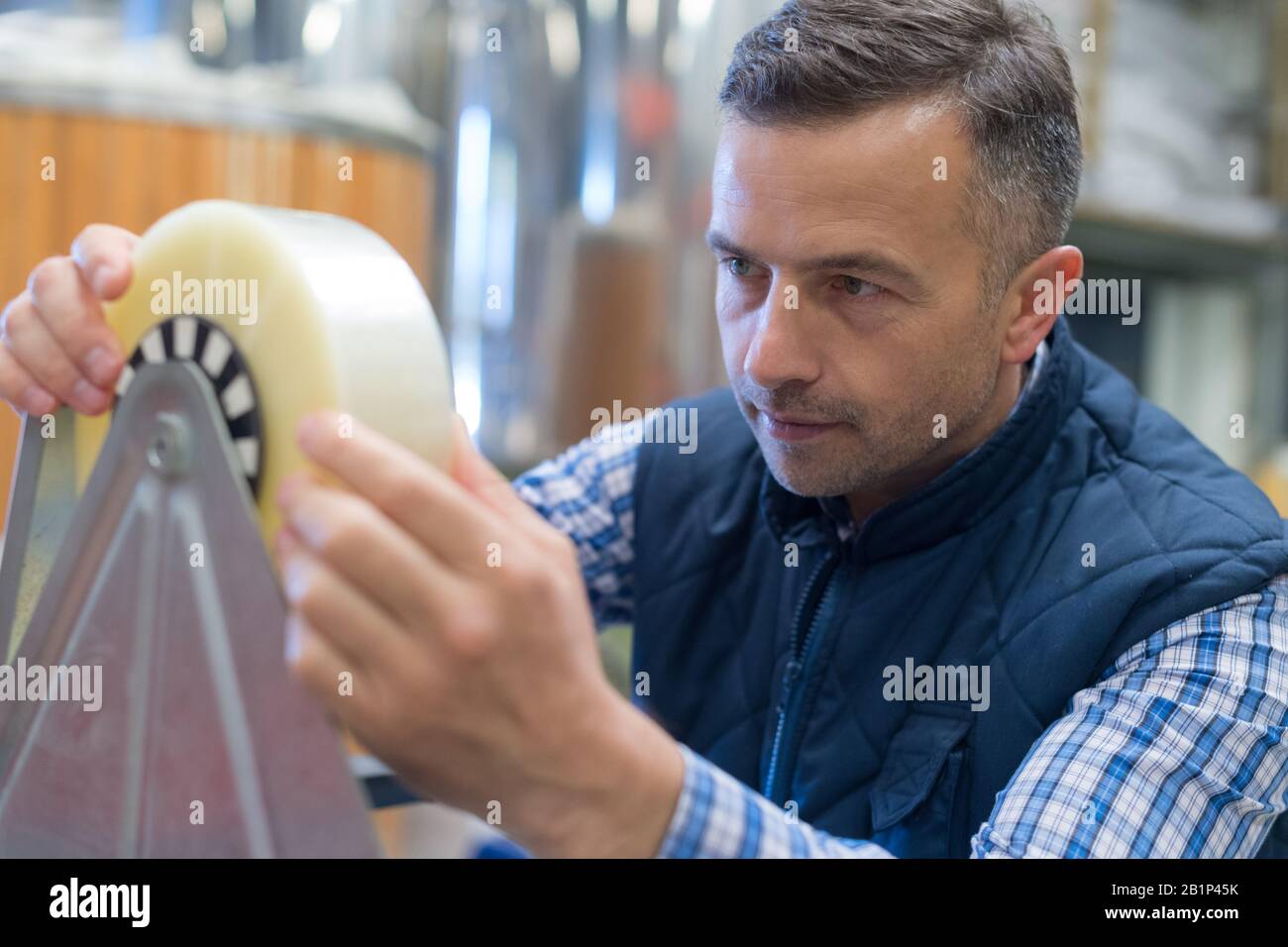 worker fitting roll of tape on production line Stock Photo - Alamy