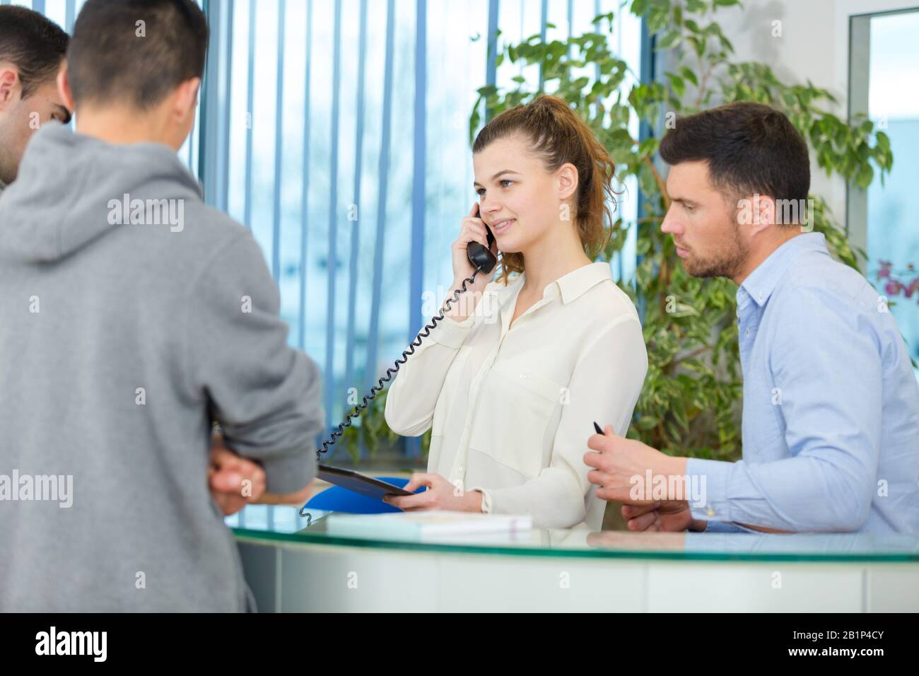 friendly young woman behind the reception desk administrator Stock ...