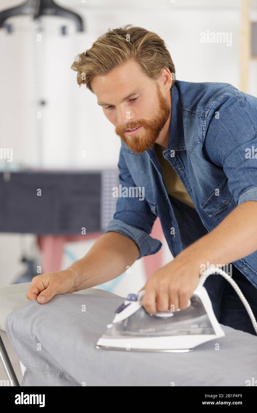 man ironing shirt on ironing board Stock Photo - Alamy