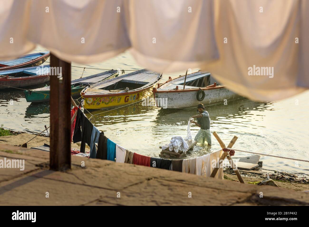 Indian man washing clothes in holy water of river Ganga in the morning ...