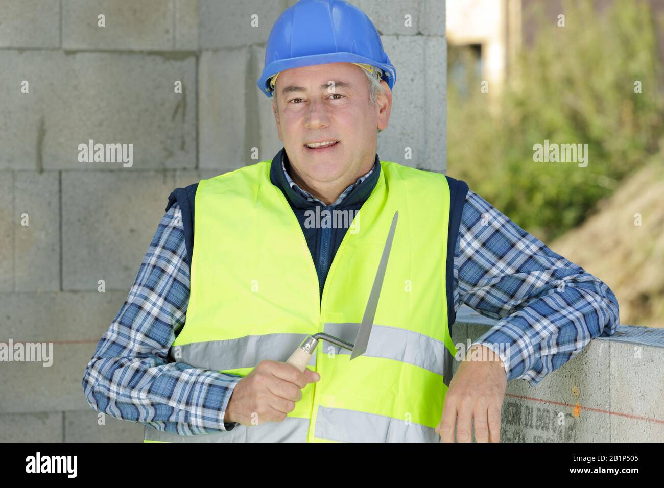 builder in a helmet holding a brick and trowel Stock Photo - Alamy