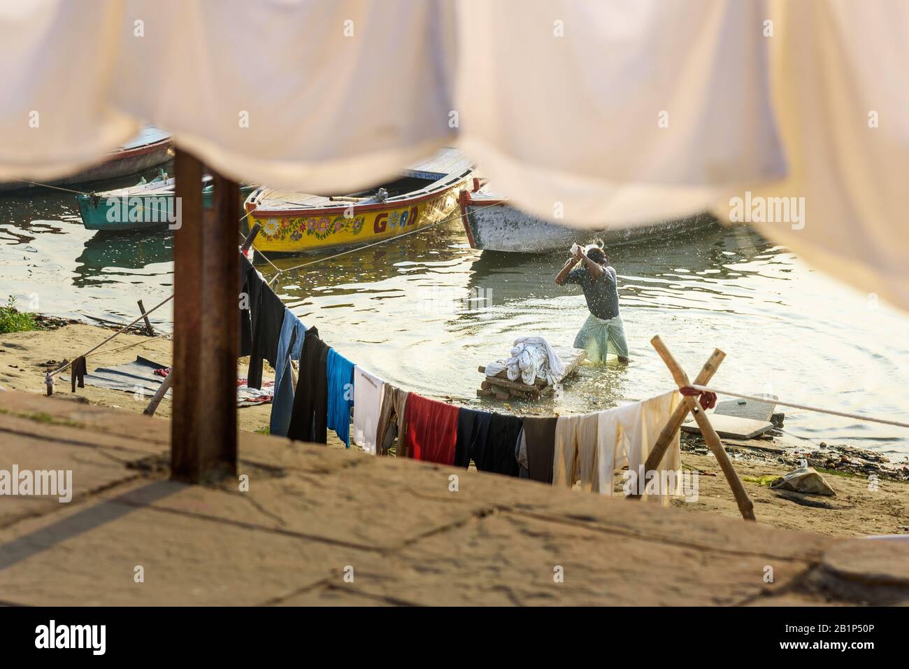 Indian man washing clothes in holy water of river Ganga in the morning ...