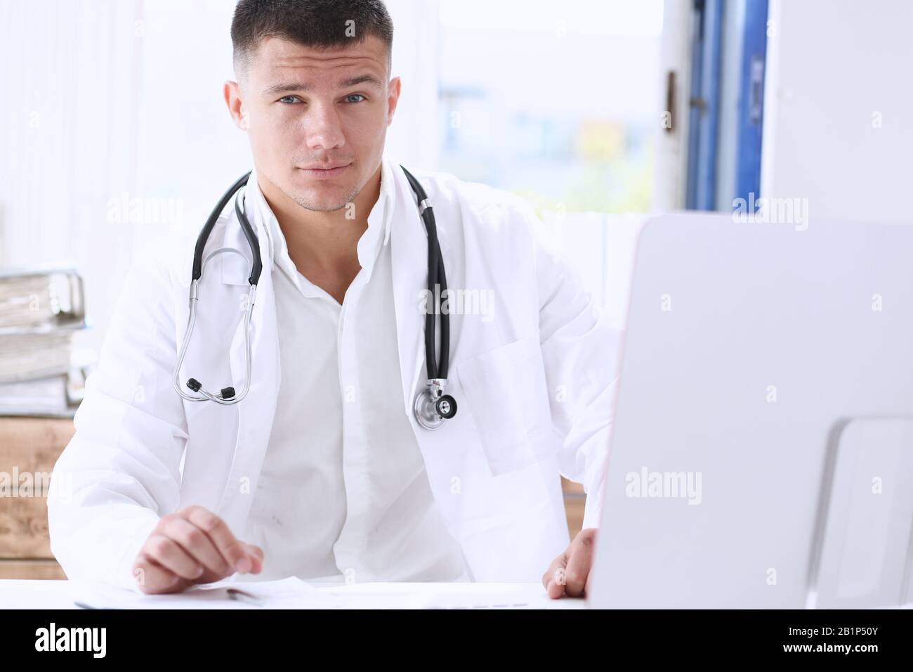 Handsome smiling male doctor write sit at workplace in office Stock ...