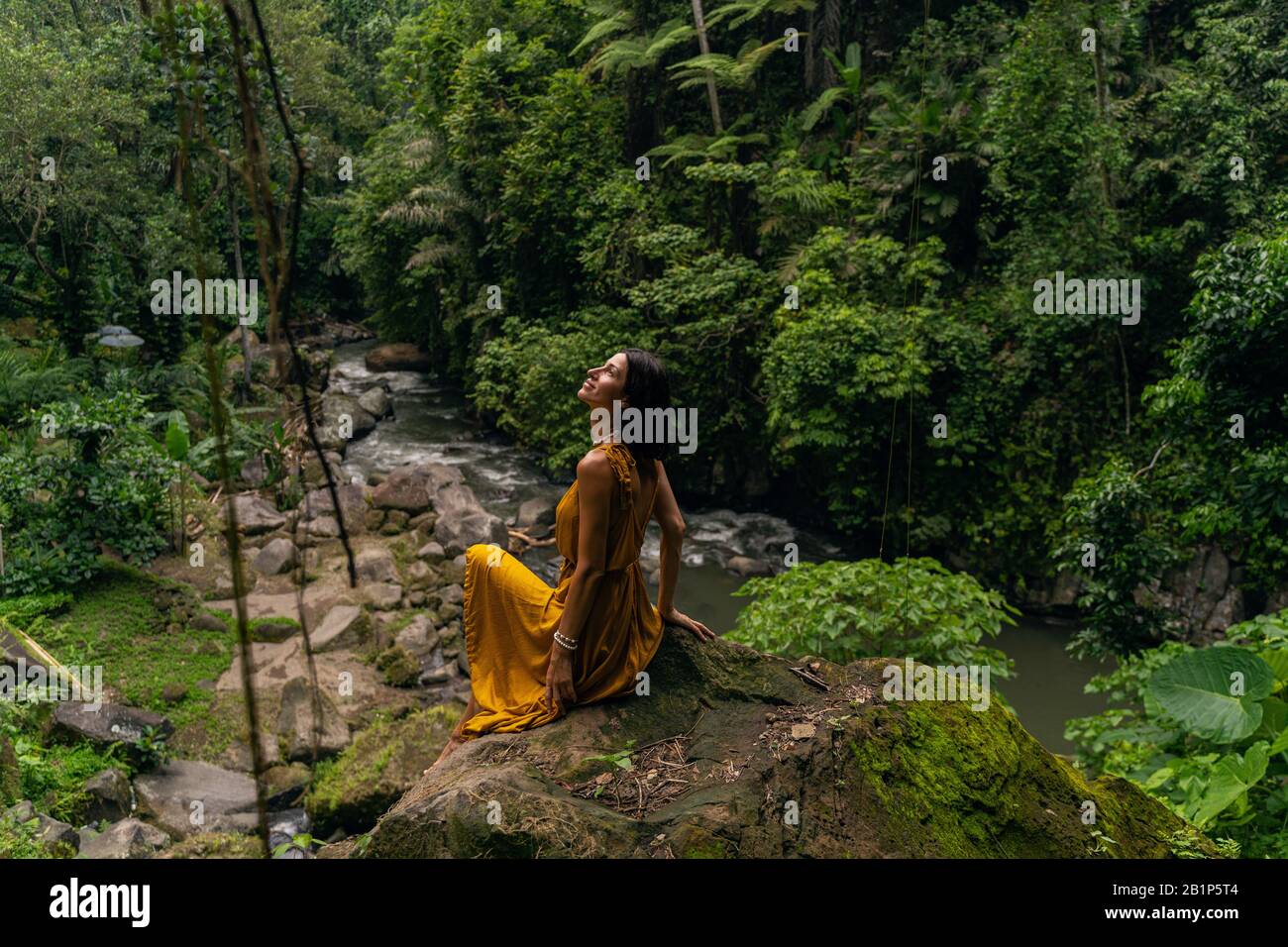 Relaxed brunette female sitting on big stone Stock Photo - Alamy